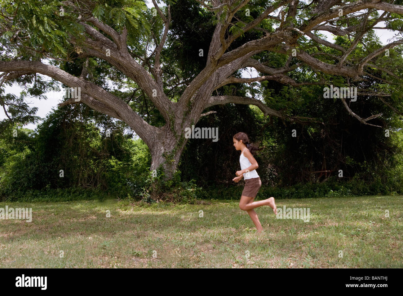 Hispanic girl running barefoot through grass Stock Photo - Alamy