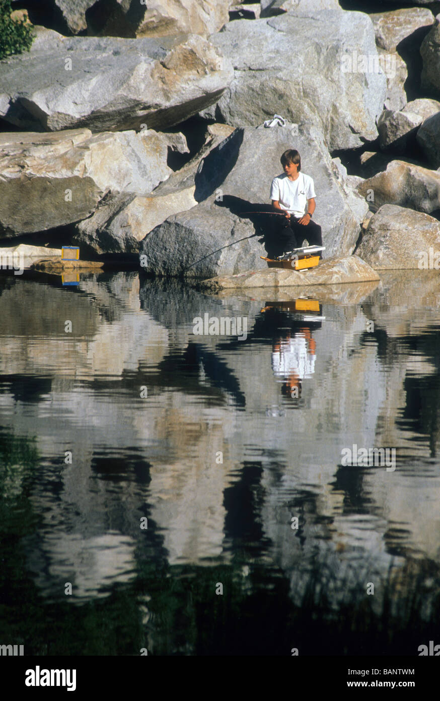 Teen boy fish reflection rock lake water sport recreation forest nature ...