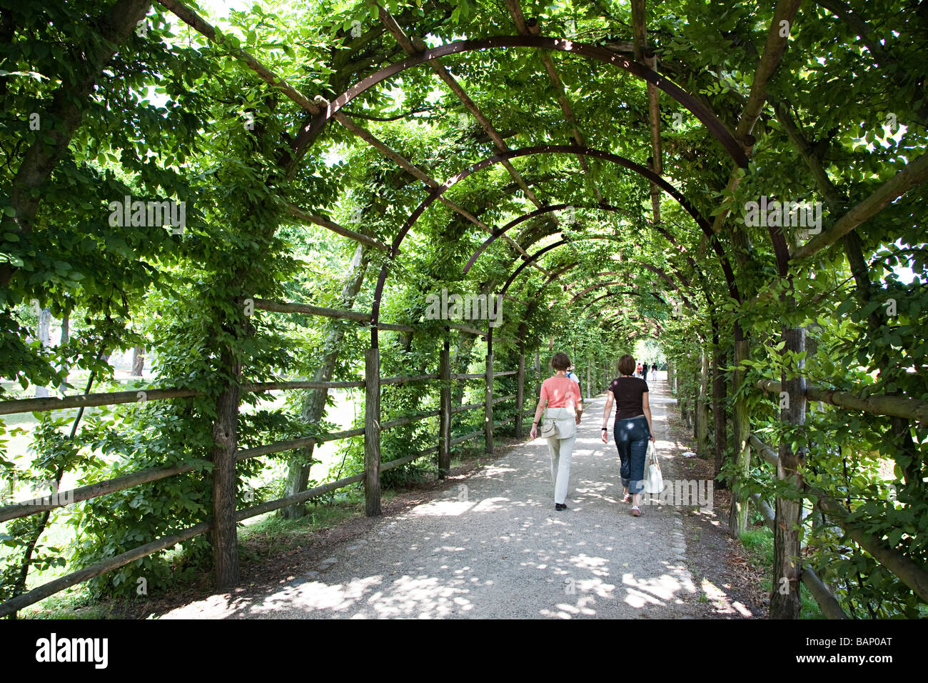 People walking on path under arches shaded with plants Schwerin Germany ...