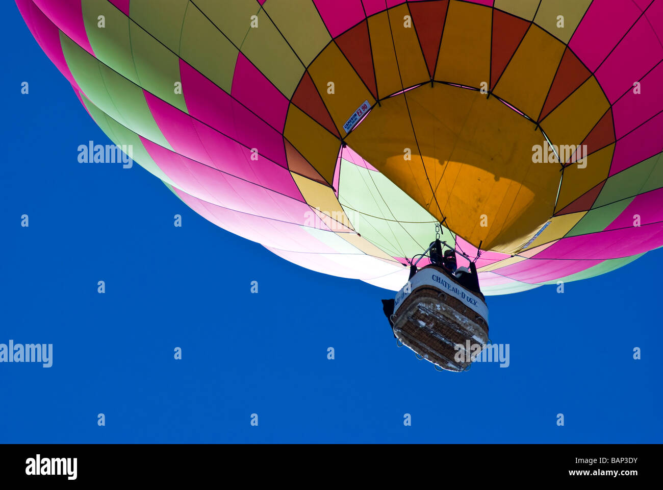 Looking up at a hot air balloon rising into the clear blue sky at the ...