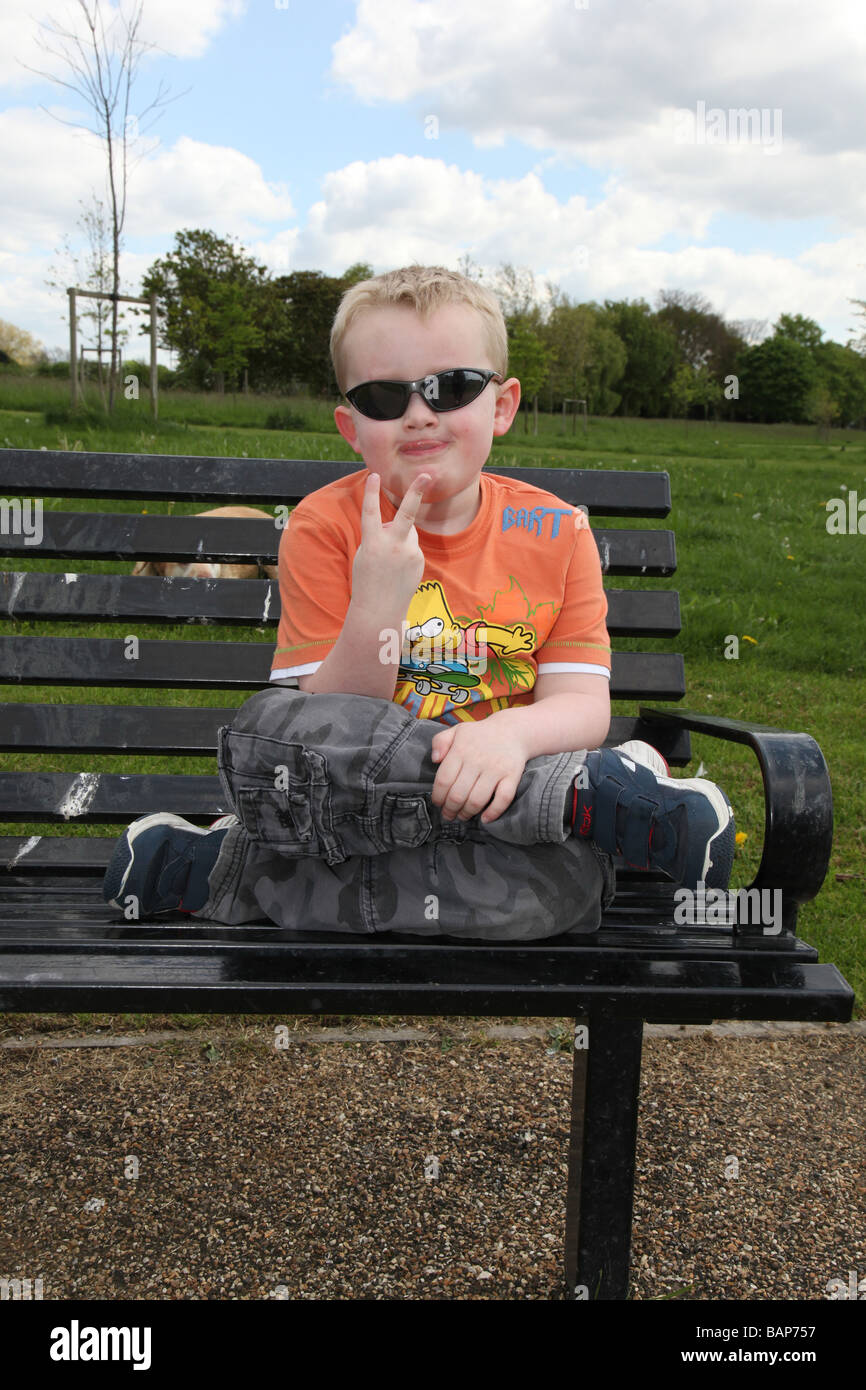 Child sitting on park bench sticking up his fingers Stock Photo - Alamy