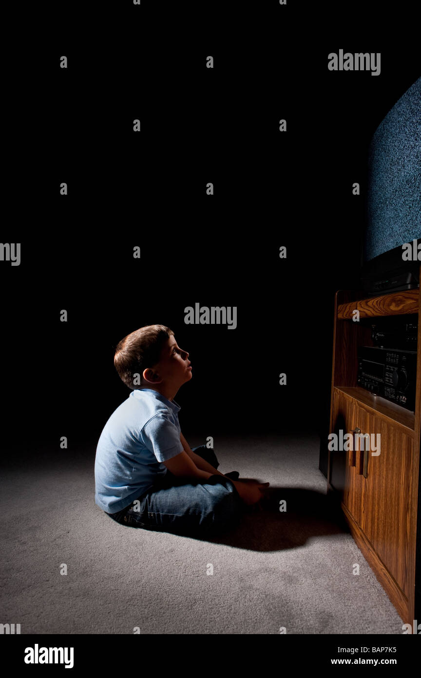 Six year old boy watching static on television in the dark Stock Photo ...
