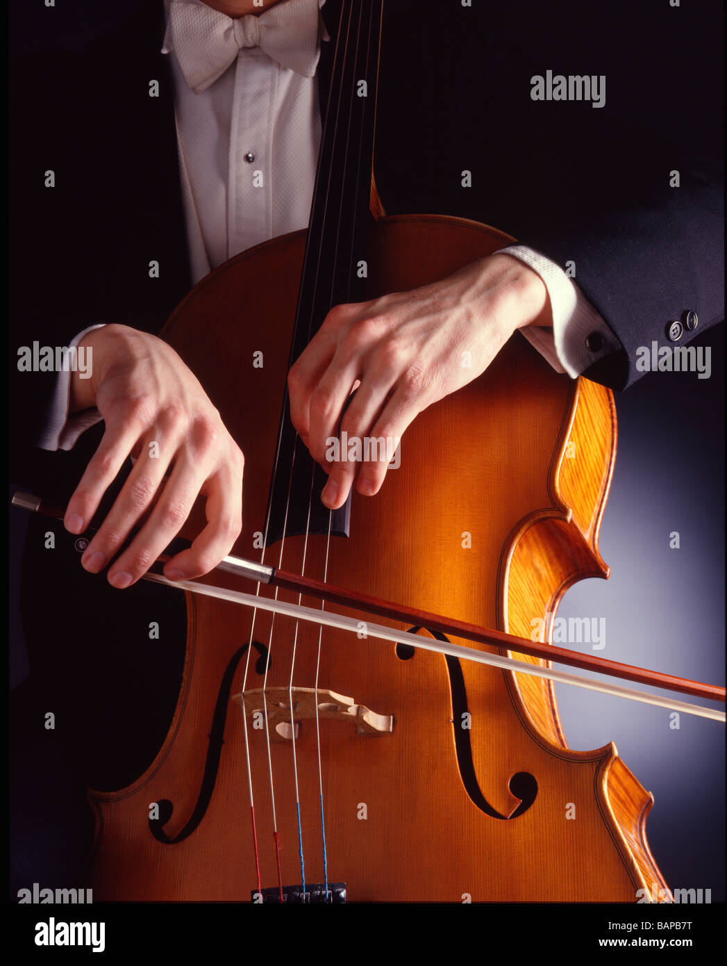 A close up of a cello player in tuxedo bowing his cello Stock Photo - Alamy
