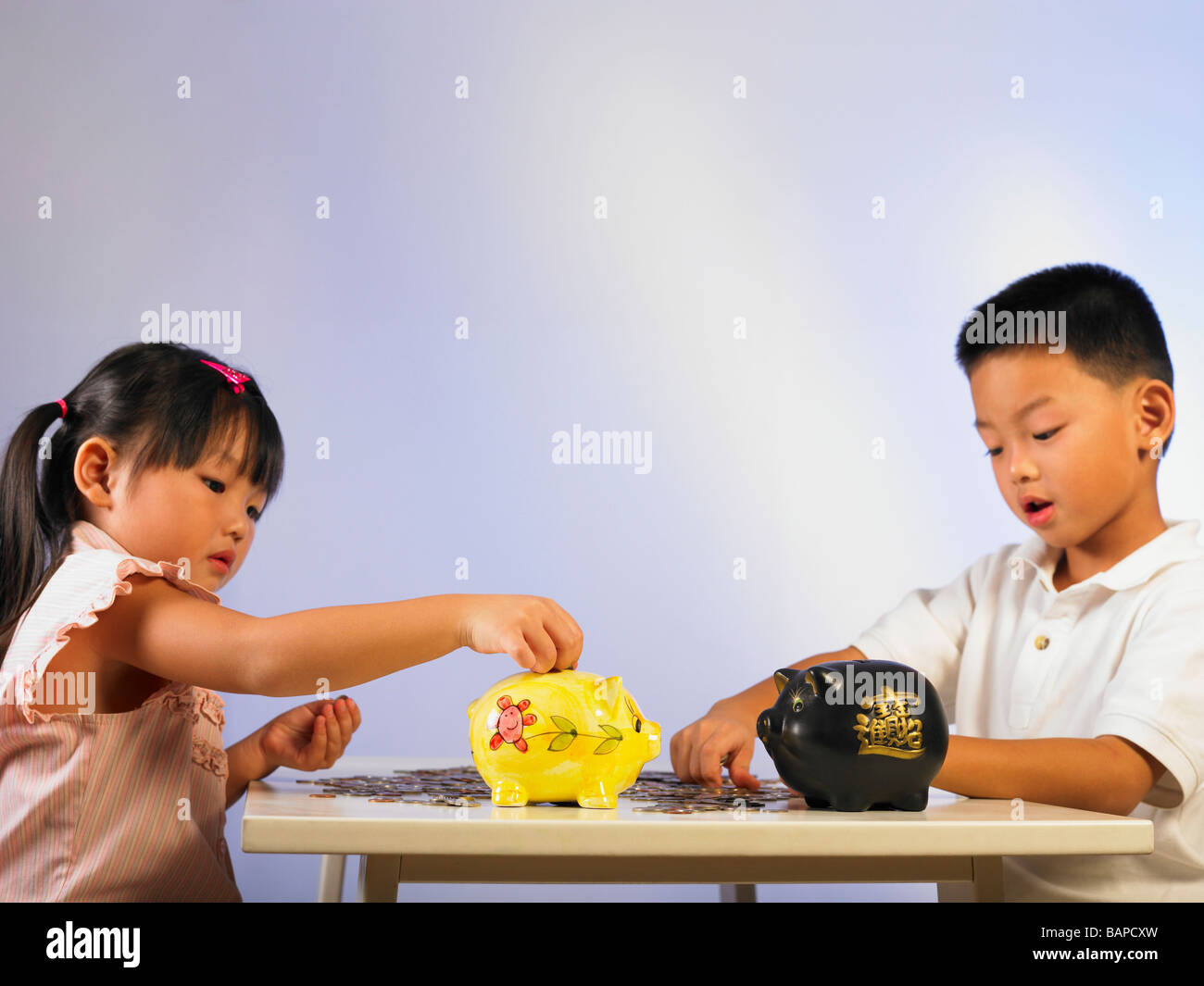 brother and sister putting saving into ha piggy bank Stock Photo - Alamy