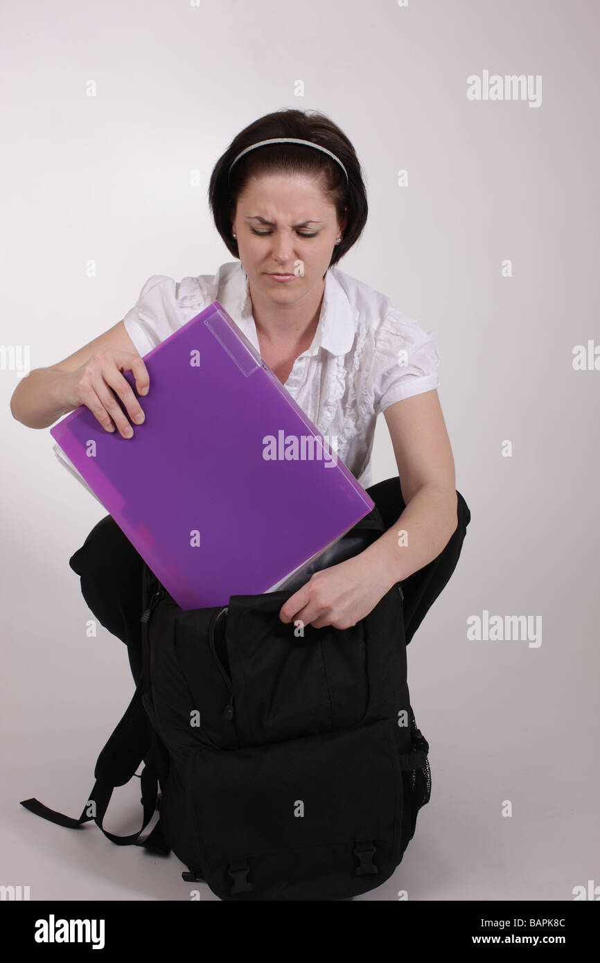 School girl putting folder with homework in bag or satchel Stock Photo ...