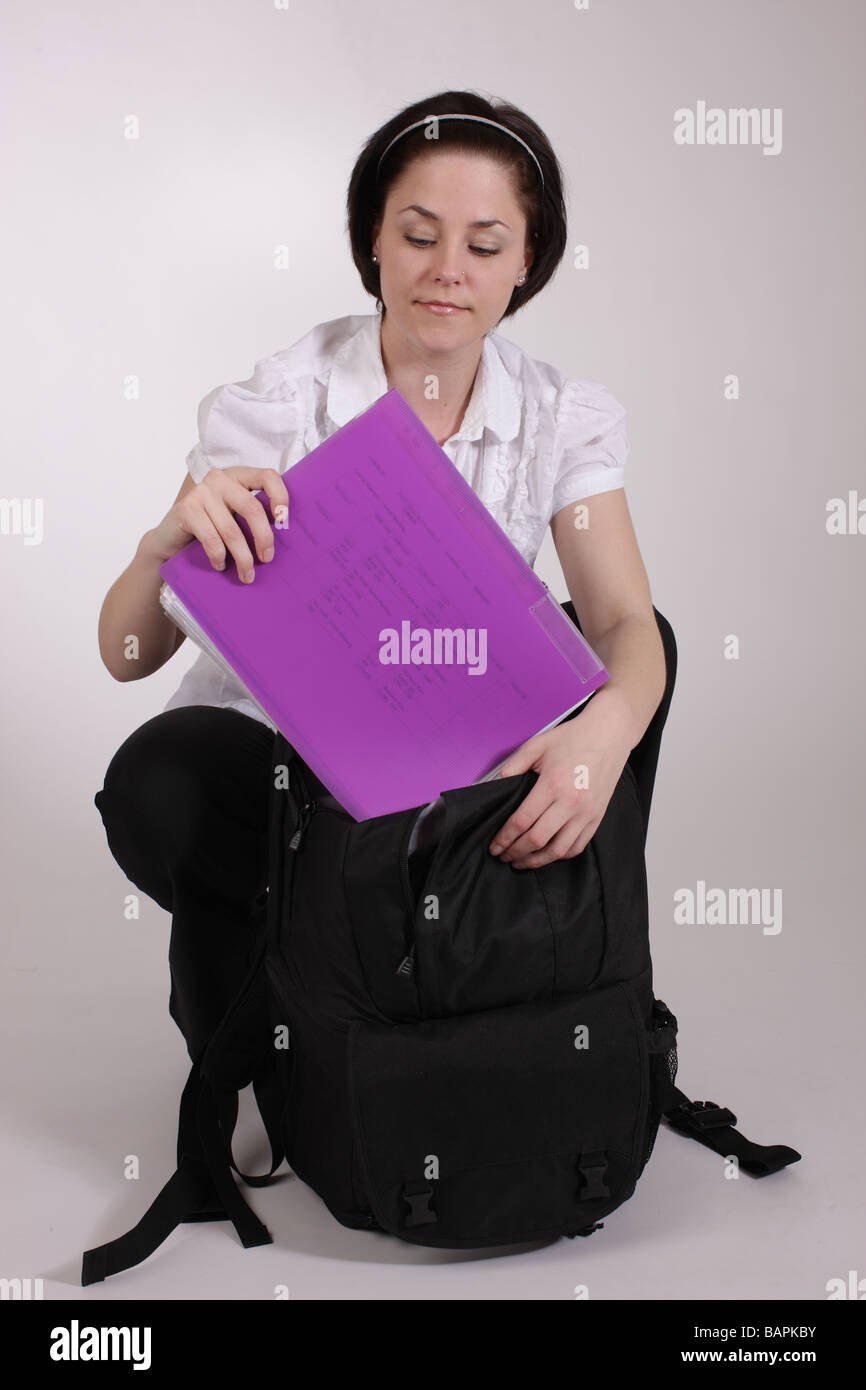 School girl putting folder with homework in bag or satchel Stock Photo ...