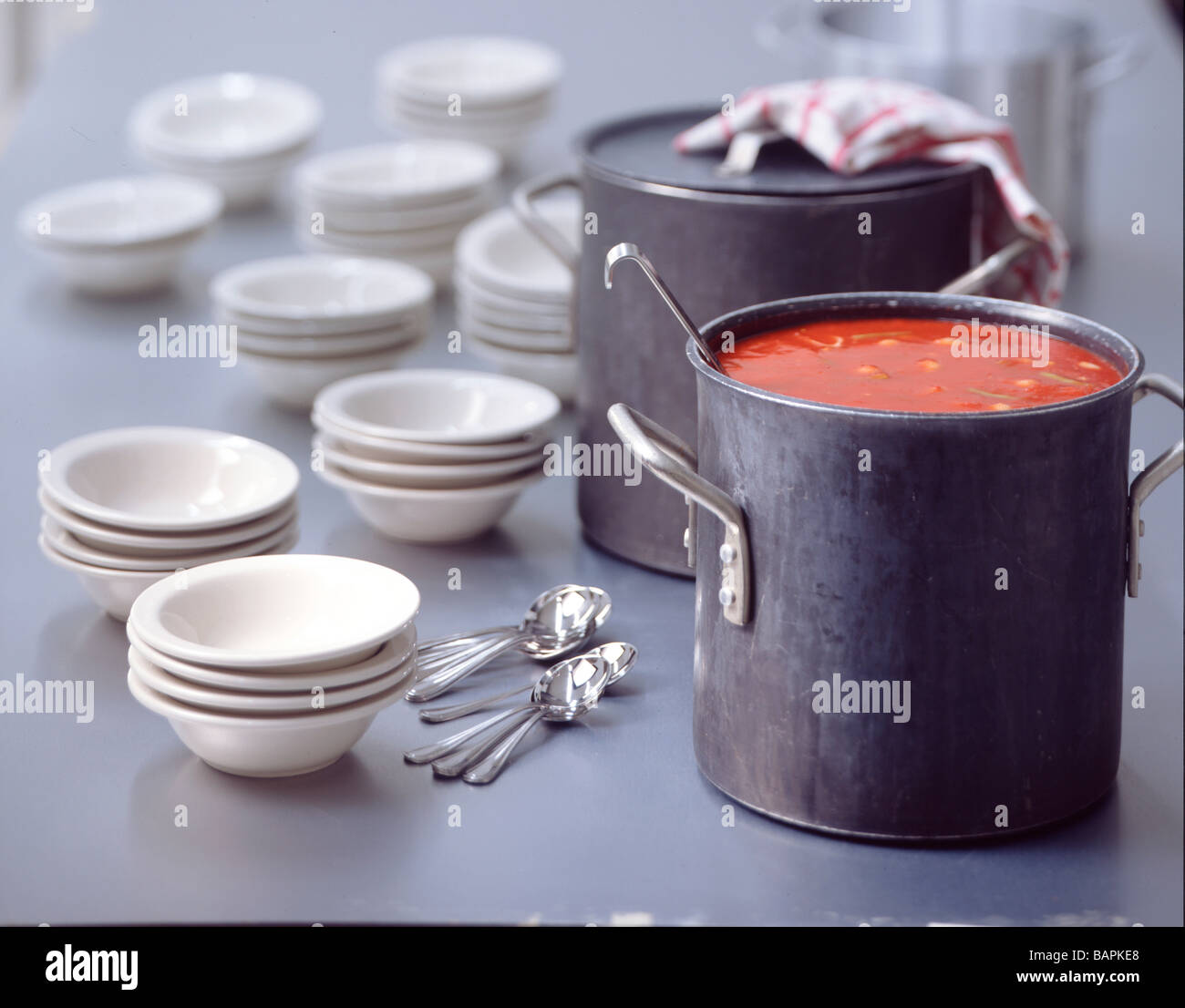 Large pots of soup and soup bowls are spread out on a countertop for ...