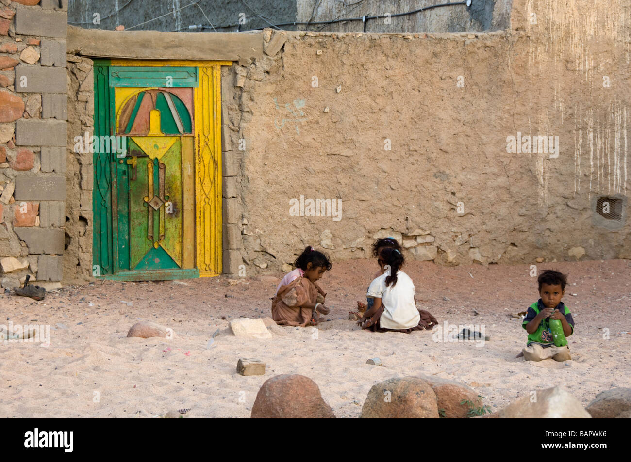 Children playing in the sand in front of their house on the island of ...