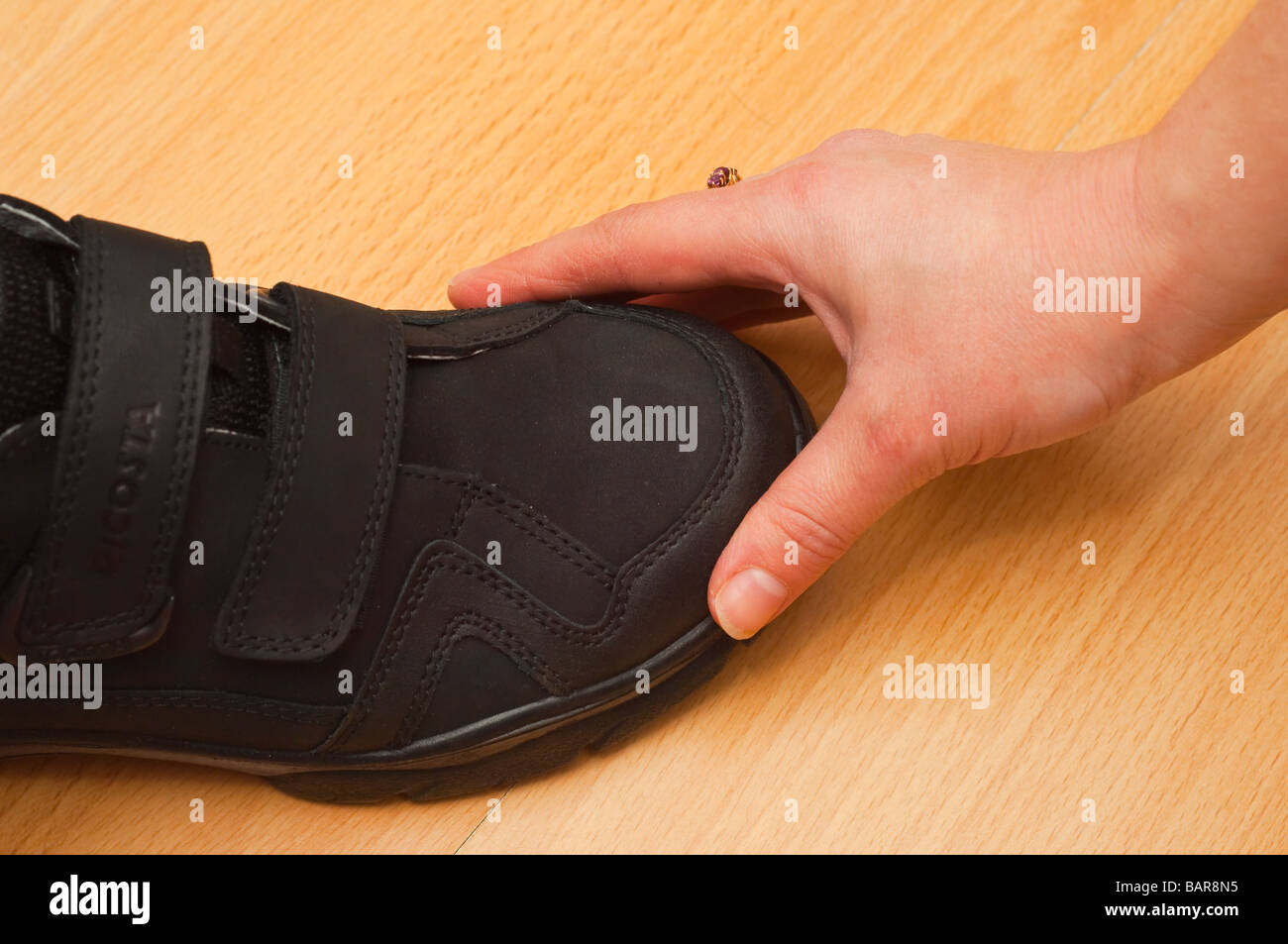 A child trying on a pair of new shoes with the shop assistant feeling ...