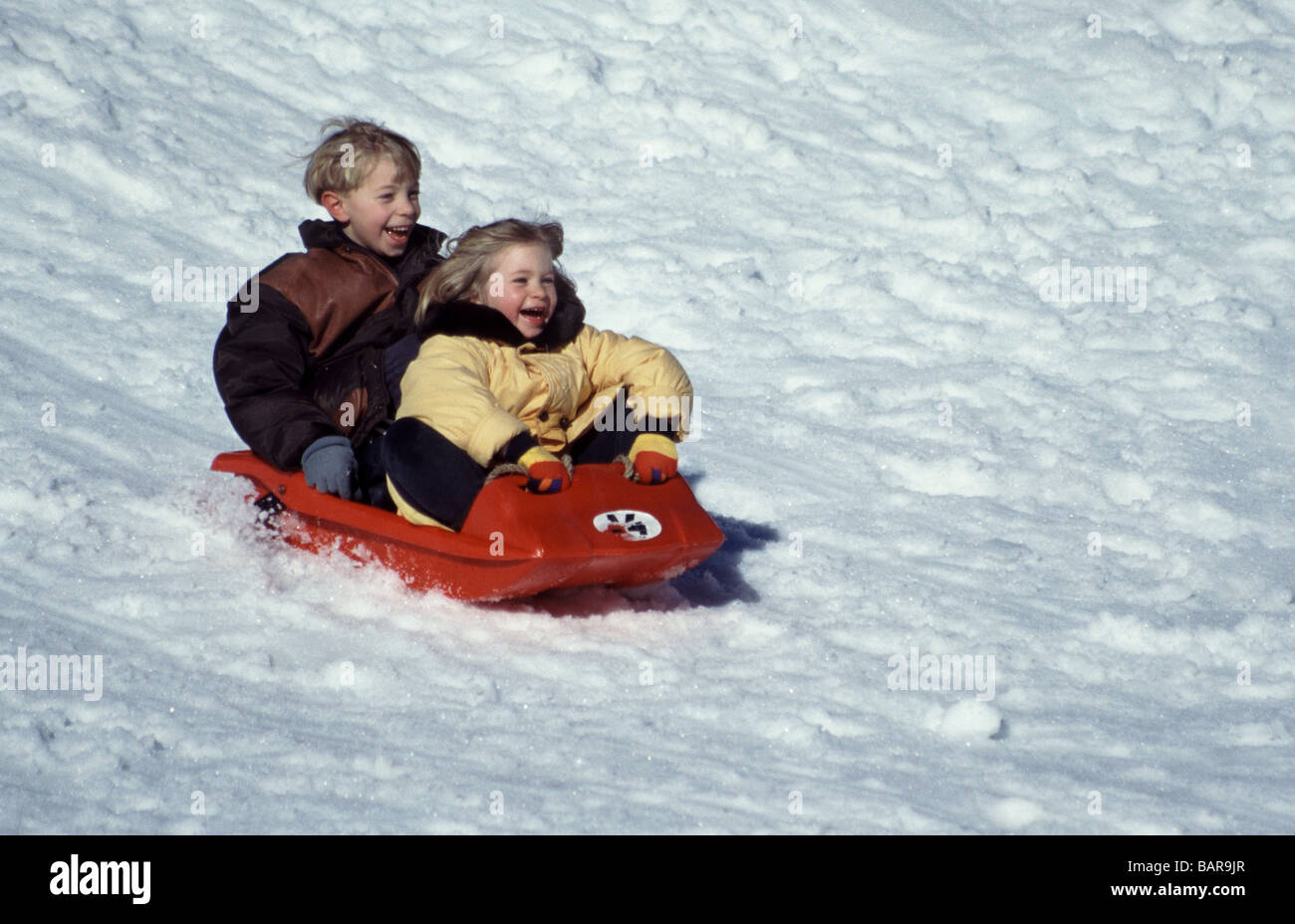 Boy and girl on a red sledge.Moving fast downhill Stock Photo - Alamy