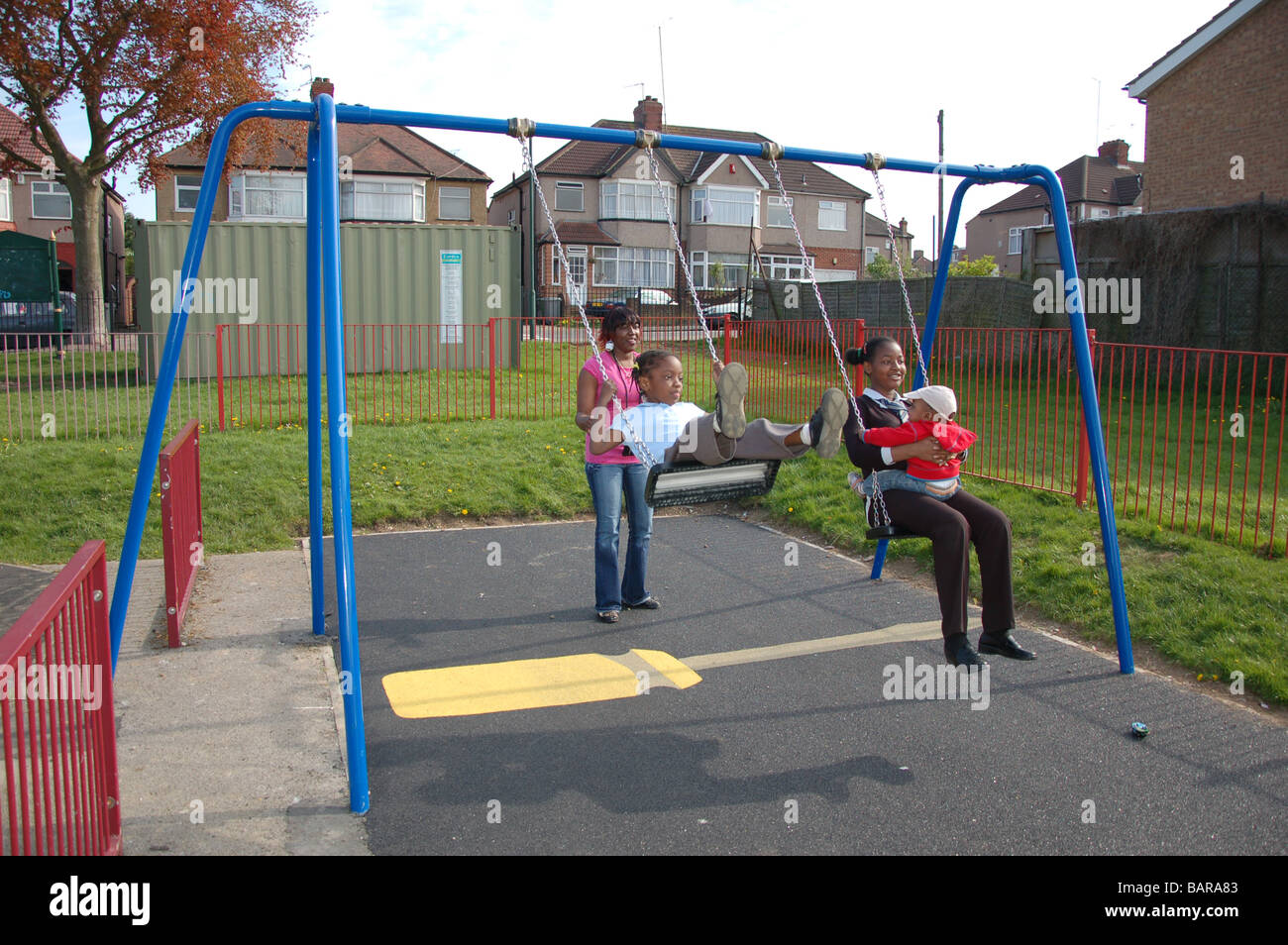 families enjoying the swings at Grove Park , Colindale, london, England ...