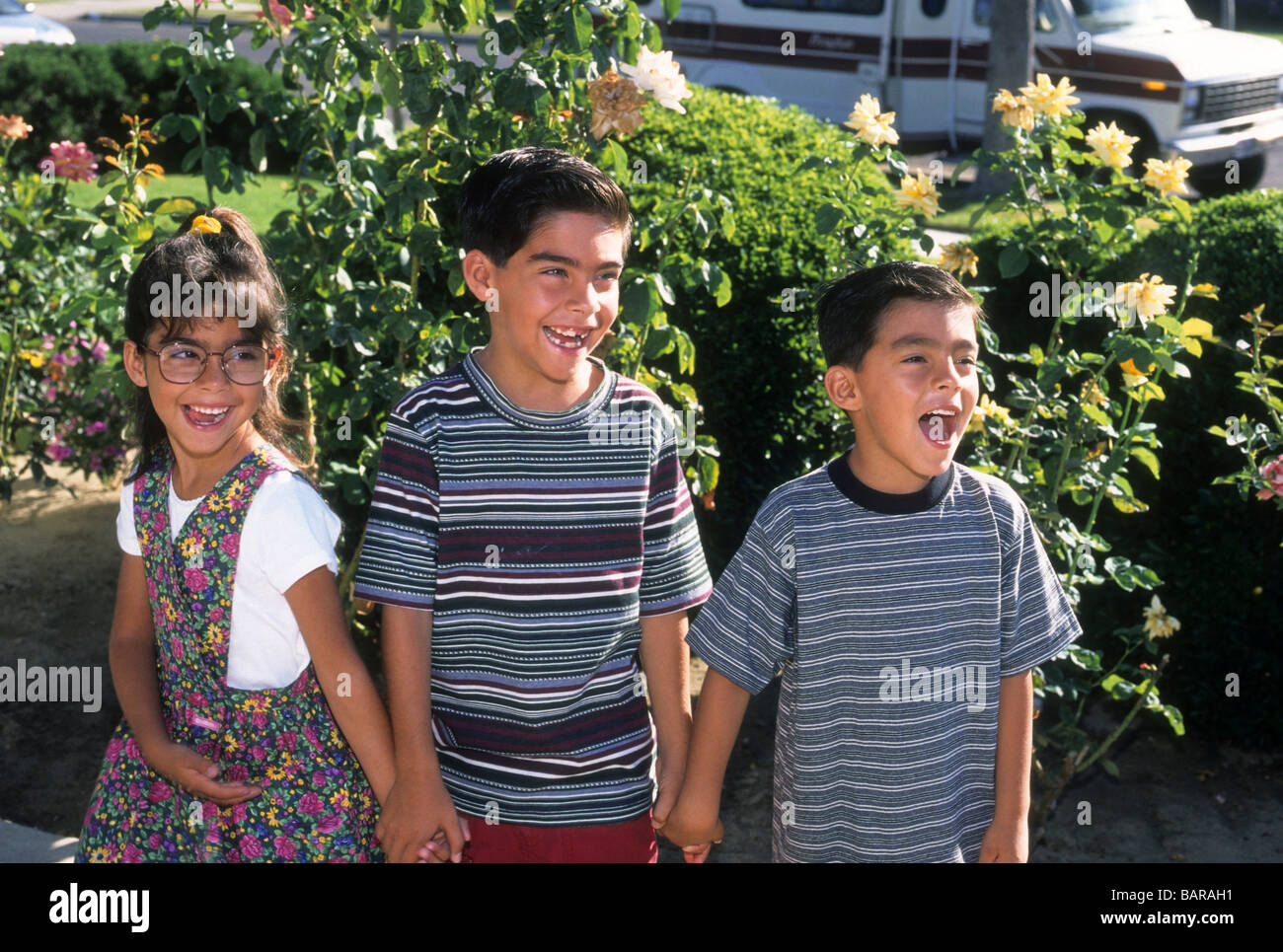 Hispanic boy and twin brother and sister smile happy portrait outdoor ...