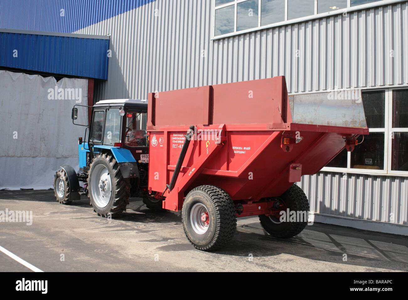 A blue tractor hauling a red grain trailer Stock Photo - Alamy