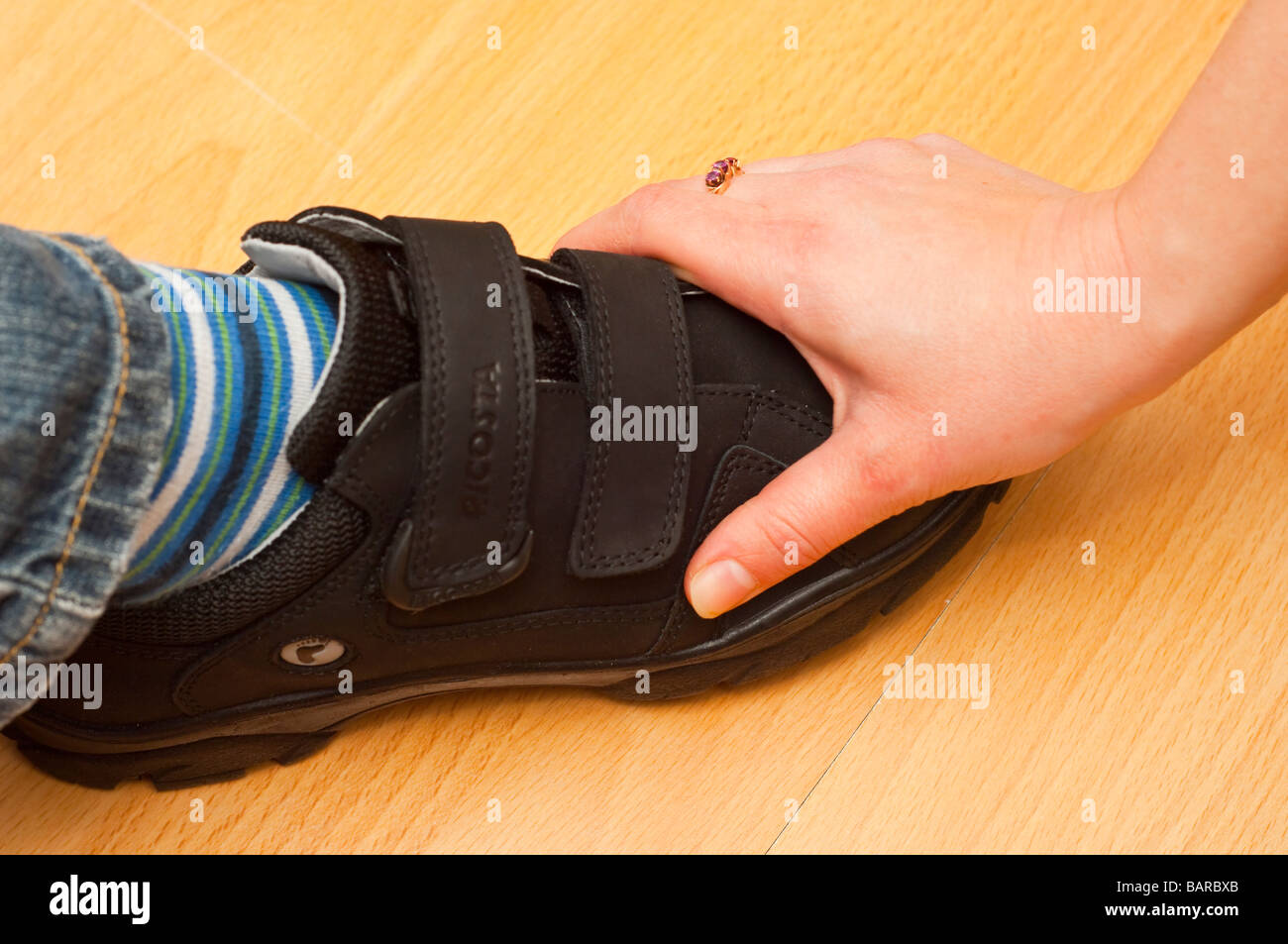 A child trying on a pair of new shoes with the shop assistant feeling ...