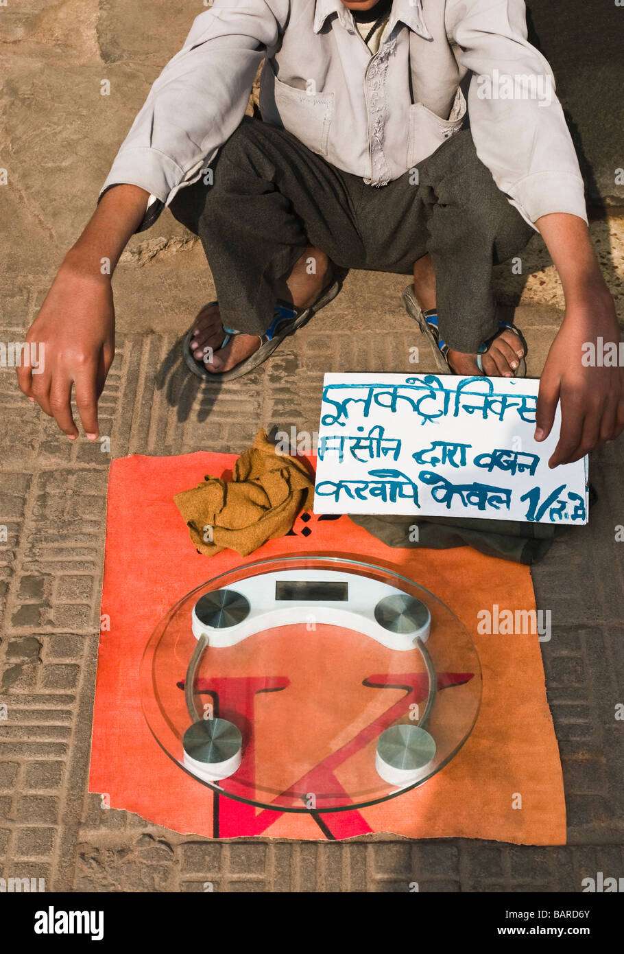 Man crouching at a sidewalk with a weighing scale, Delhi, India Stock ...