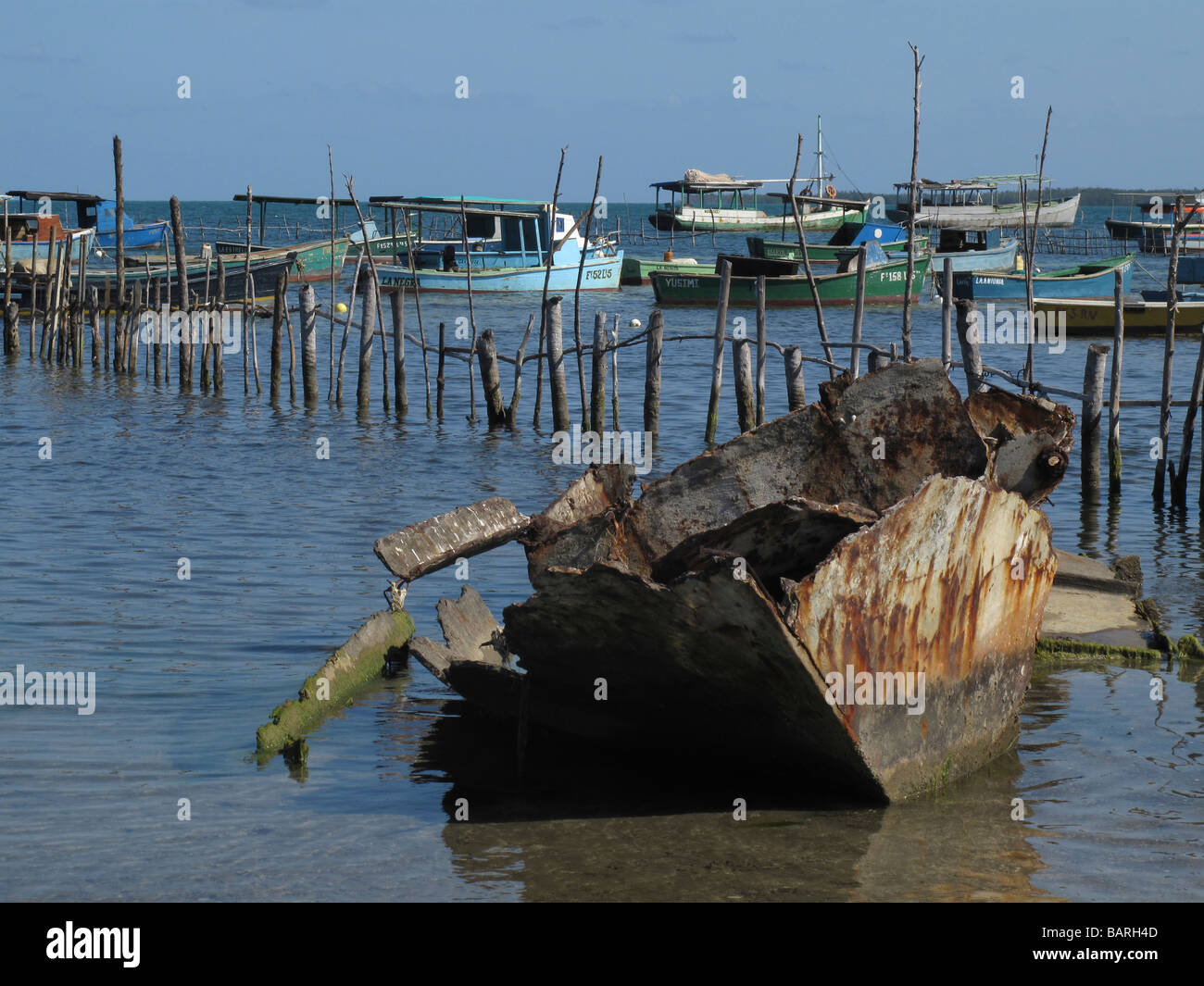 small fishing boats and a rusting wreck on a calm blue sea, Puerto ...