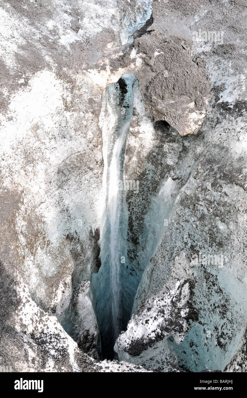 Meltwater stream plunging down a deep pot-hole or 'glacial mill' in the ...