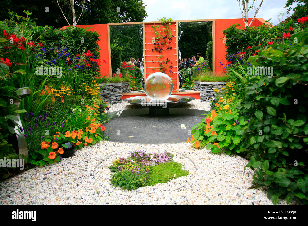 Large glass orb water feature on a paved circle surrouded by a mirrored ...