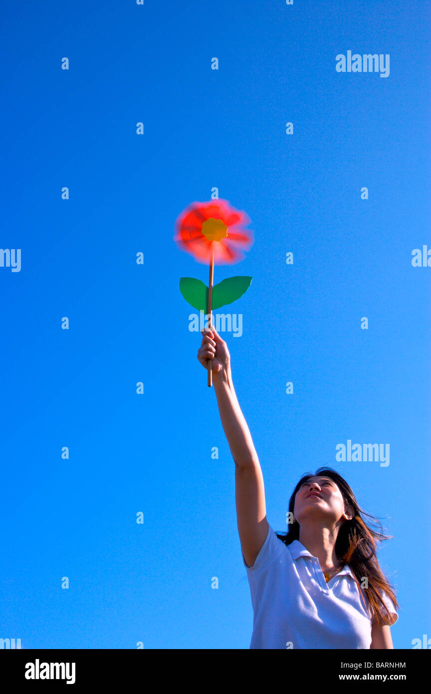 Young woman raising red flower up against blue sky Stock Photo - Alamy