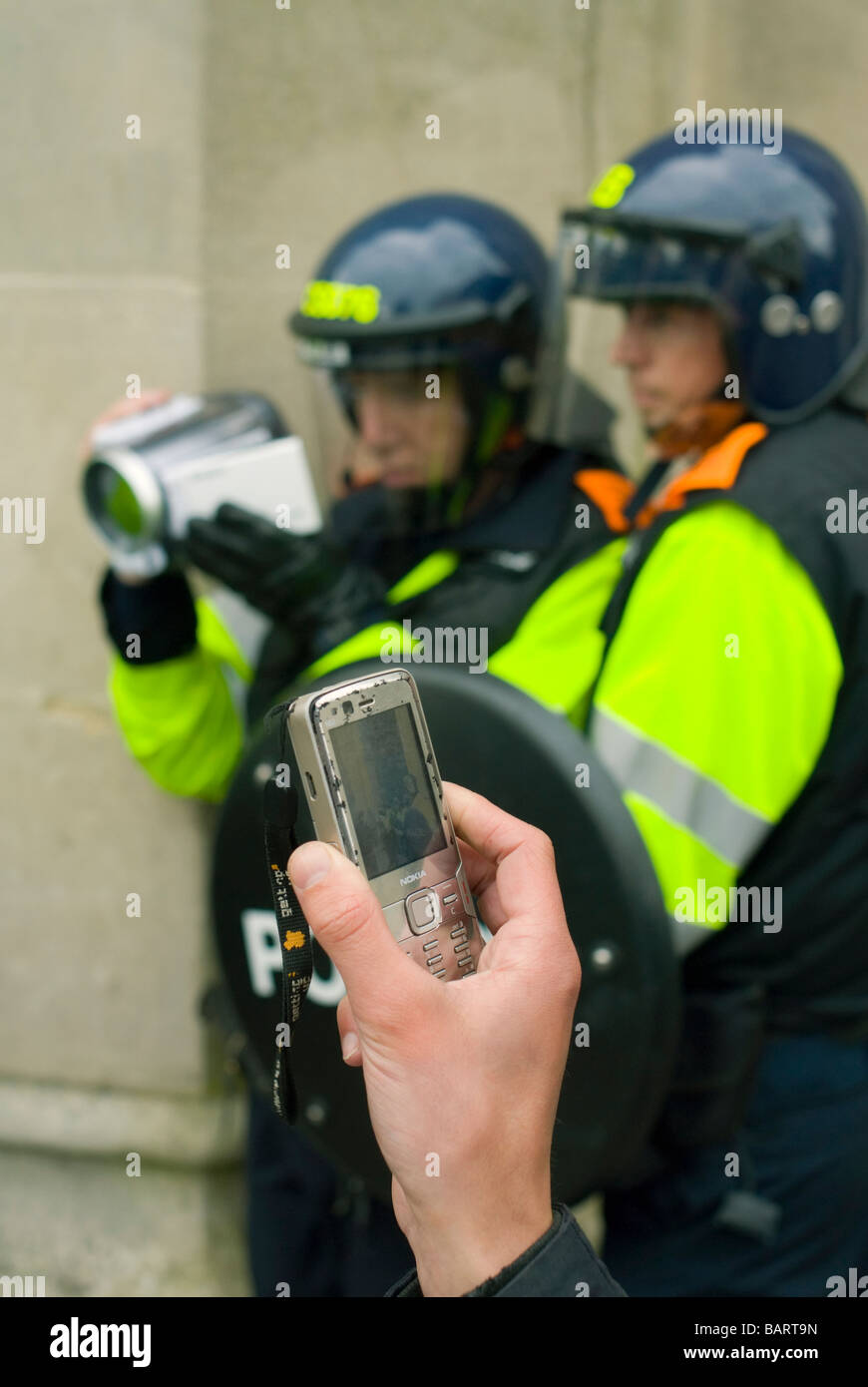 A man photographs police officers filming demonstrators on his mobile ...