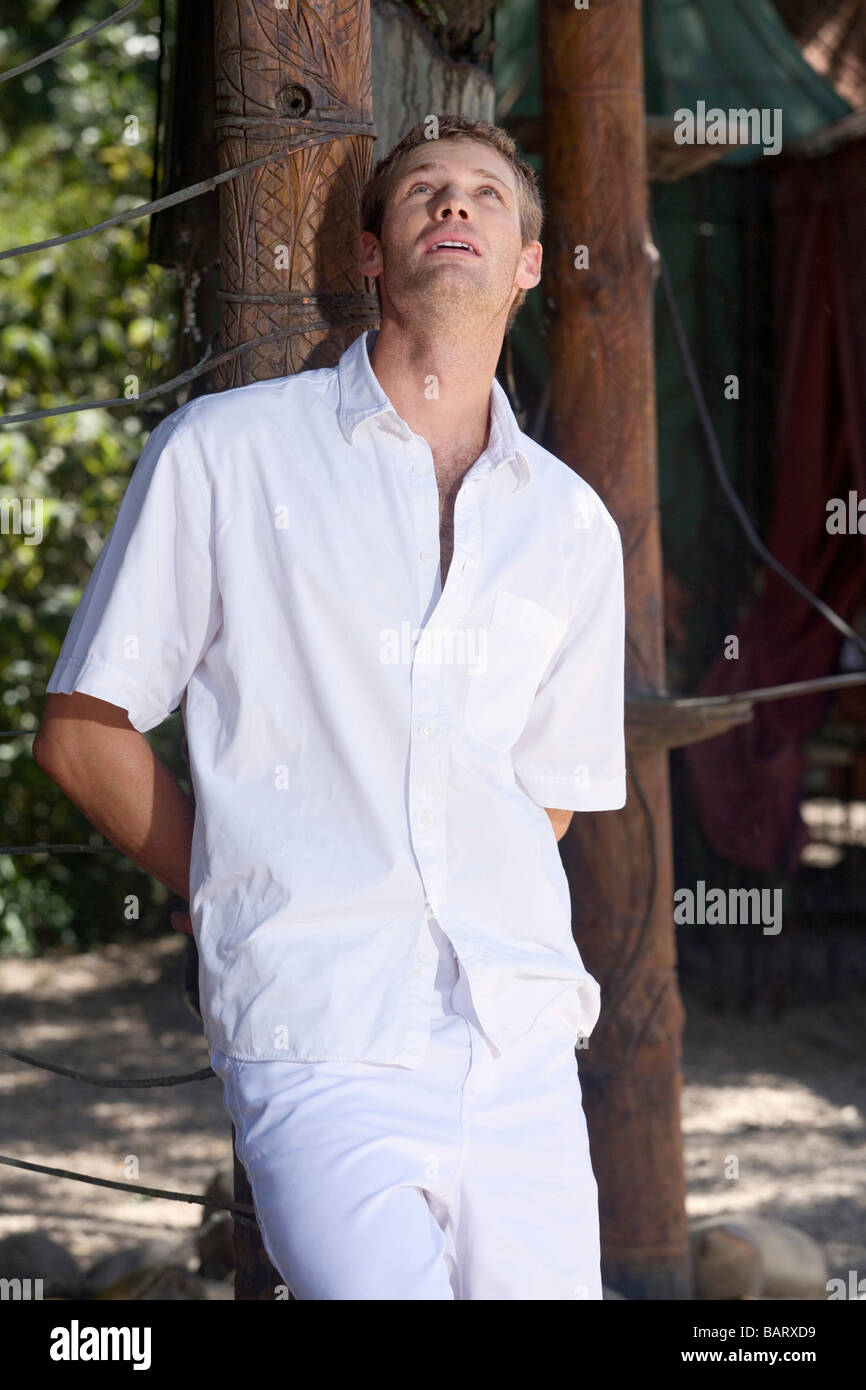 Young man leaning on post, looking up Stock Photo - Alamy