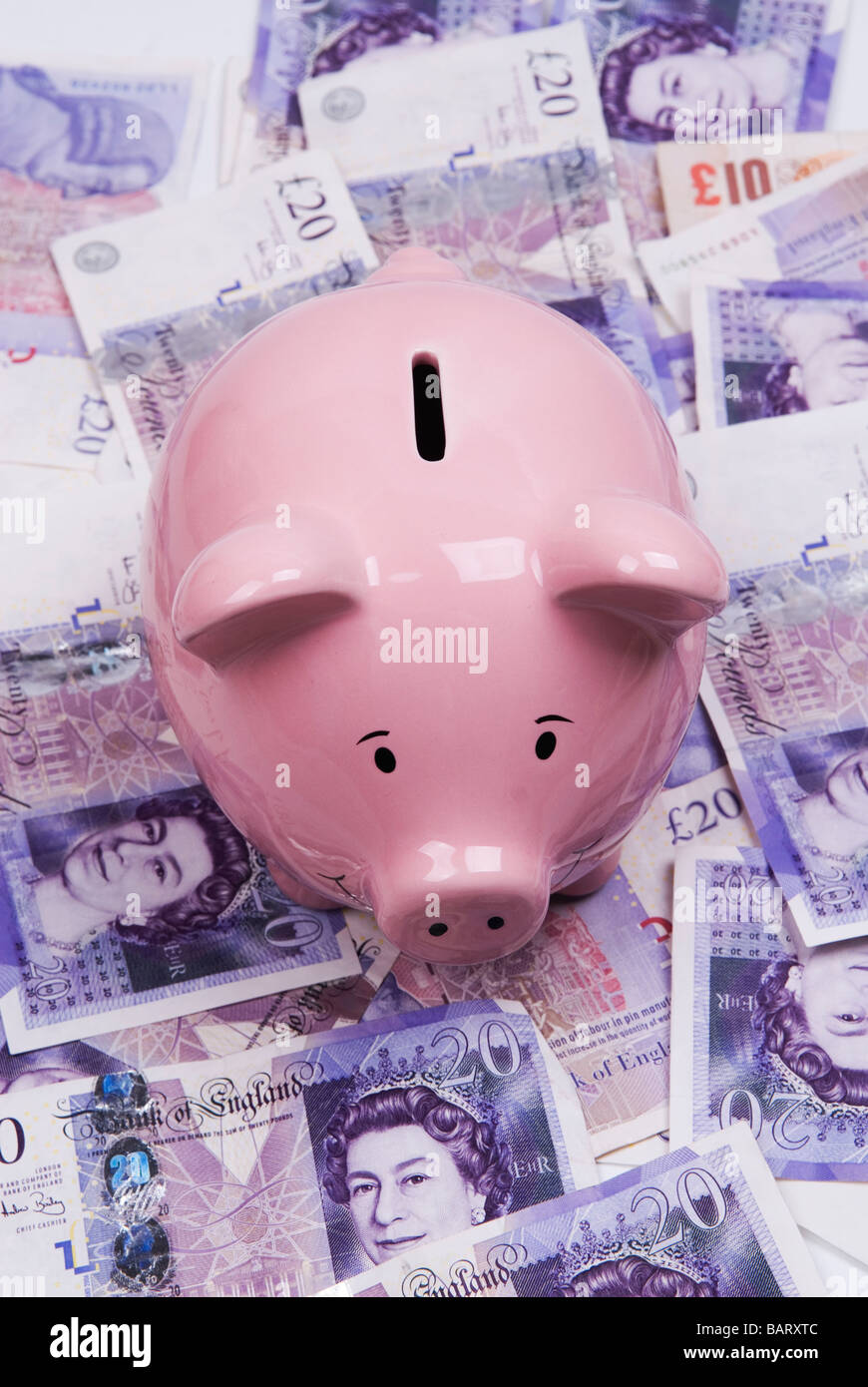 Pink piggy bank over a pile of British money Stock Photo - Alamy