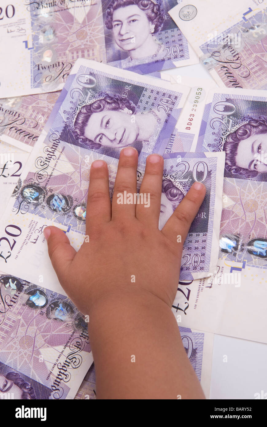 Child's hand over a pile of British money Stock Photo - Alamy