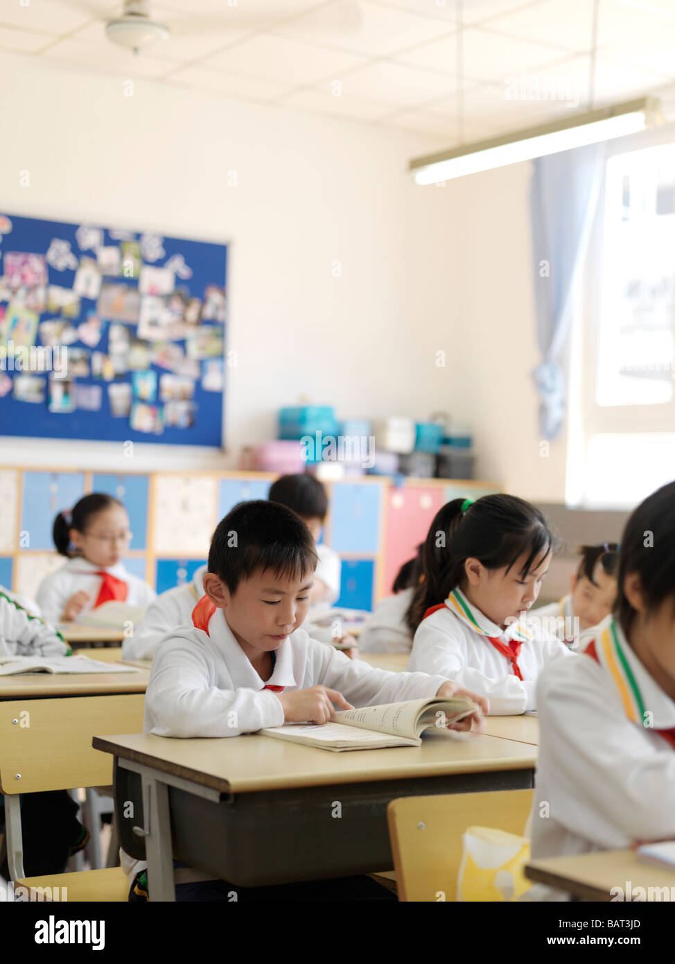 A classroom of young students reading a lesson from their textbook ...
