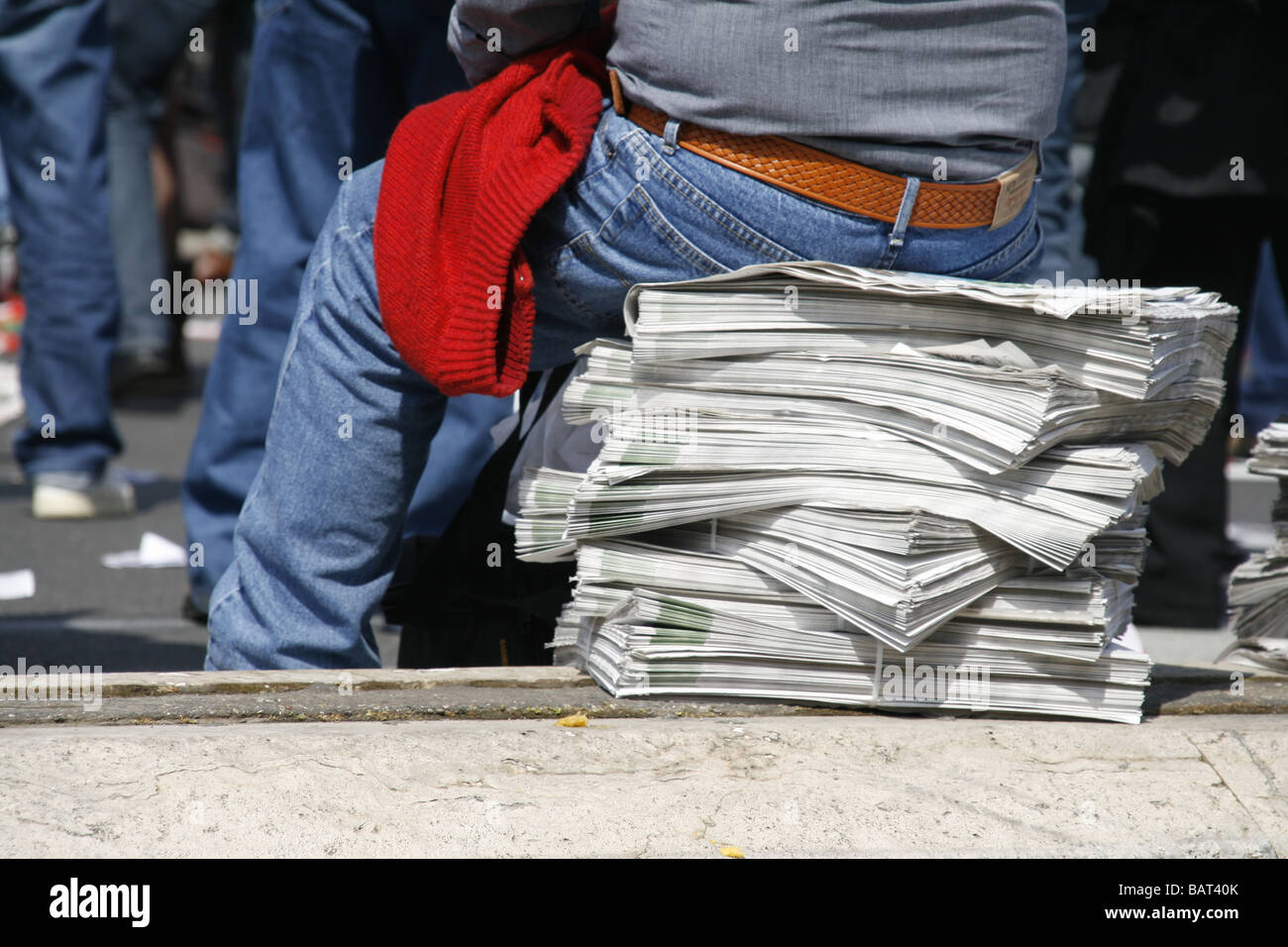 man sitting on a pile of newspapers in street in city town Stock Photo ...