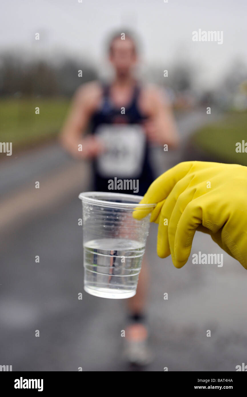 male runner in long distance road race picking up drinking water from ...