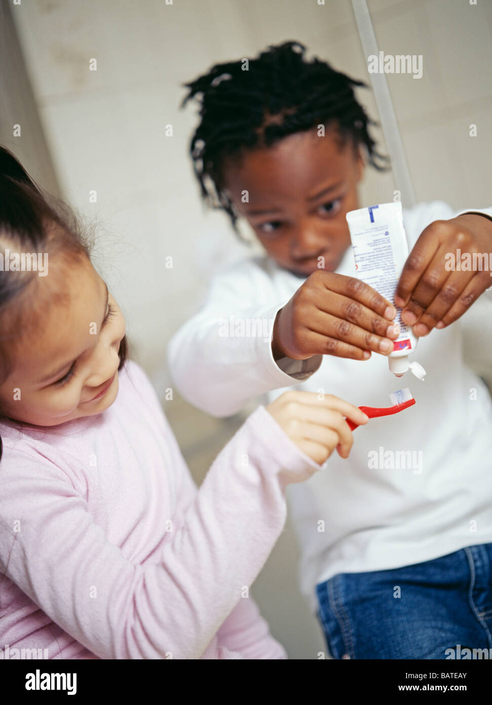 Toothbrushing. Five year old girl and boy put toothpaste on a ...
