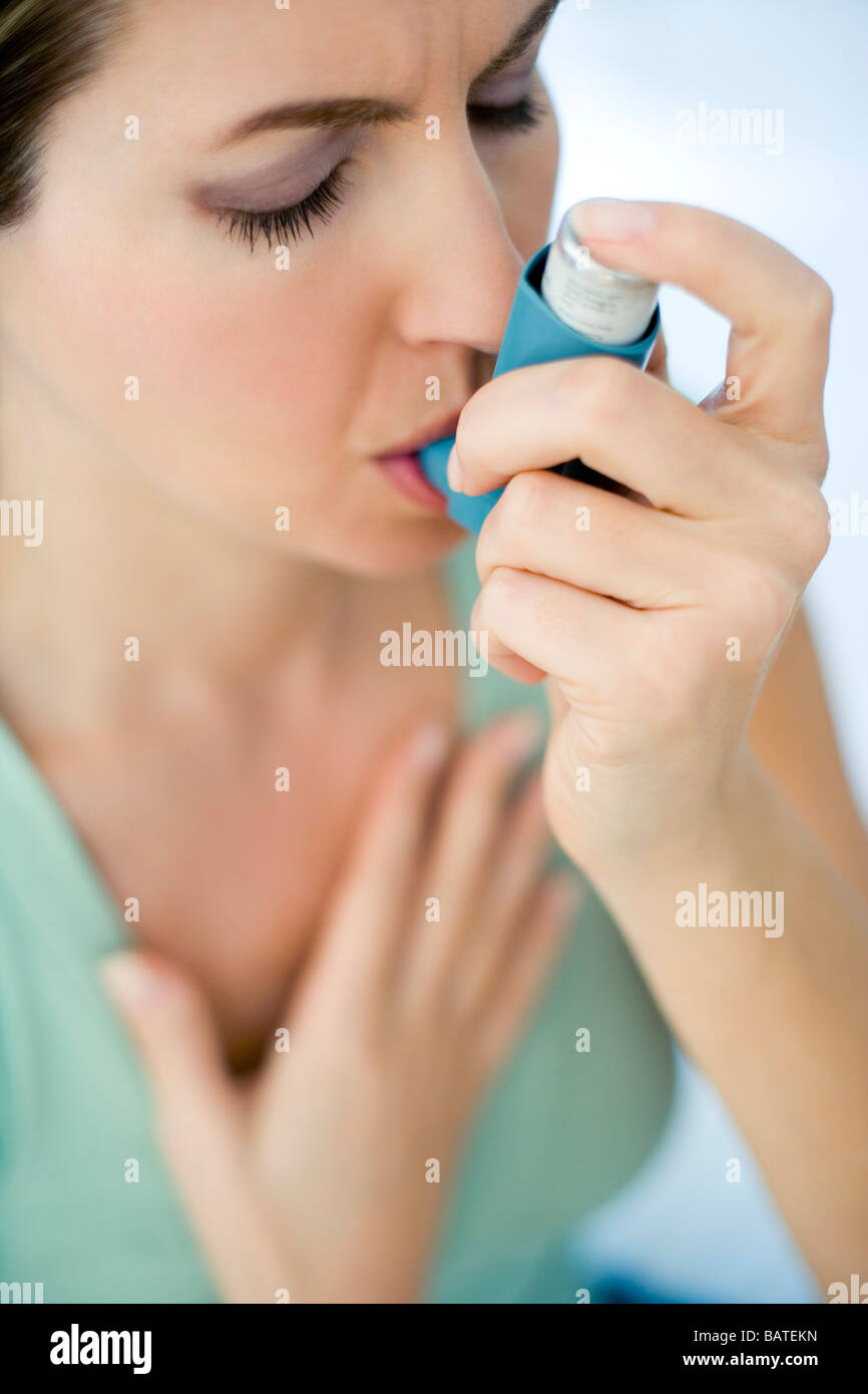 Asthma inhaler use. Woman using an inhaler to treat an asthma attack ...