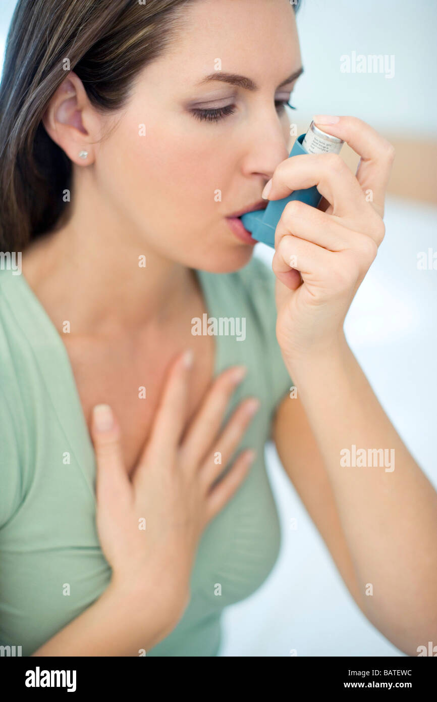 Asthma inhaler use. Woman using aninhaler to treat an asthma attack ...