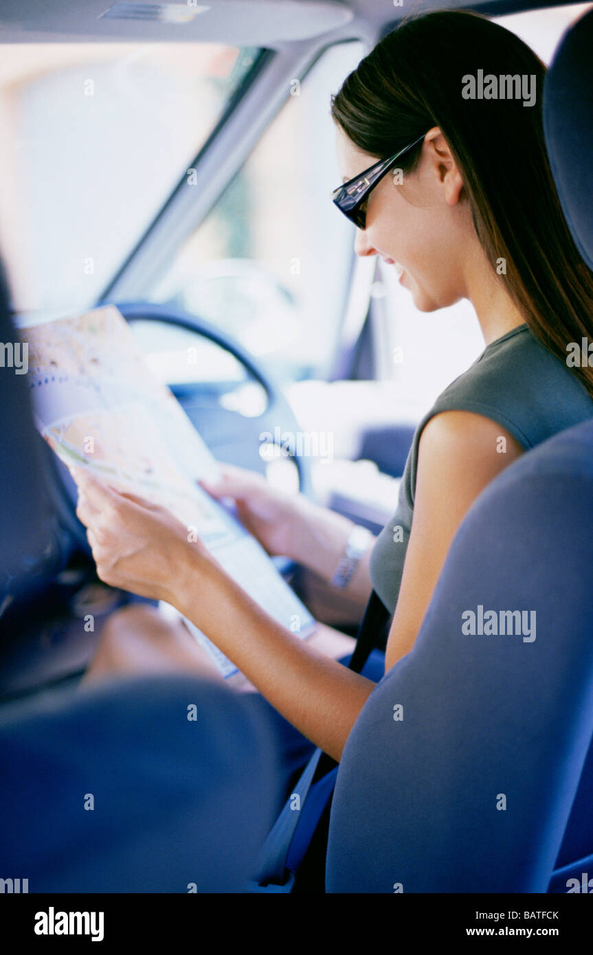 Road navigation. Woman driverreading a raod map before starting her ...