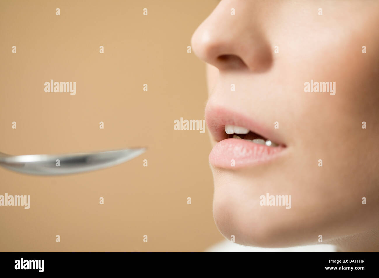 young woman taking syrup from a spoon Stock Photo - Alamy