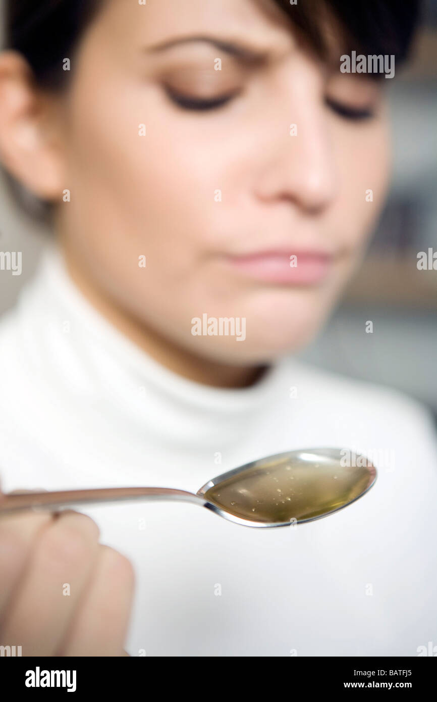 young woman taking syrup from a spoon Stock Photo - Alamy