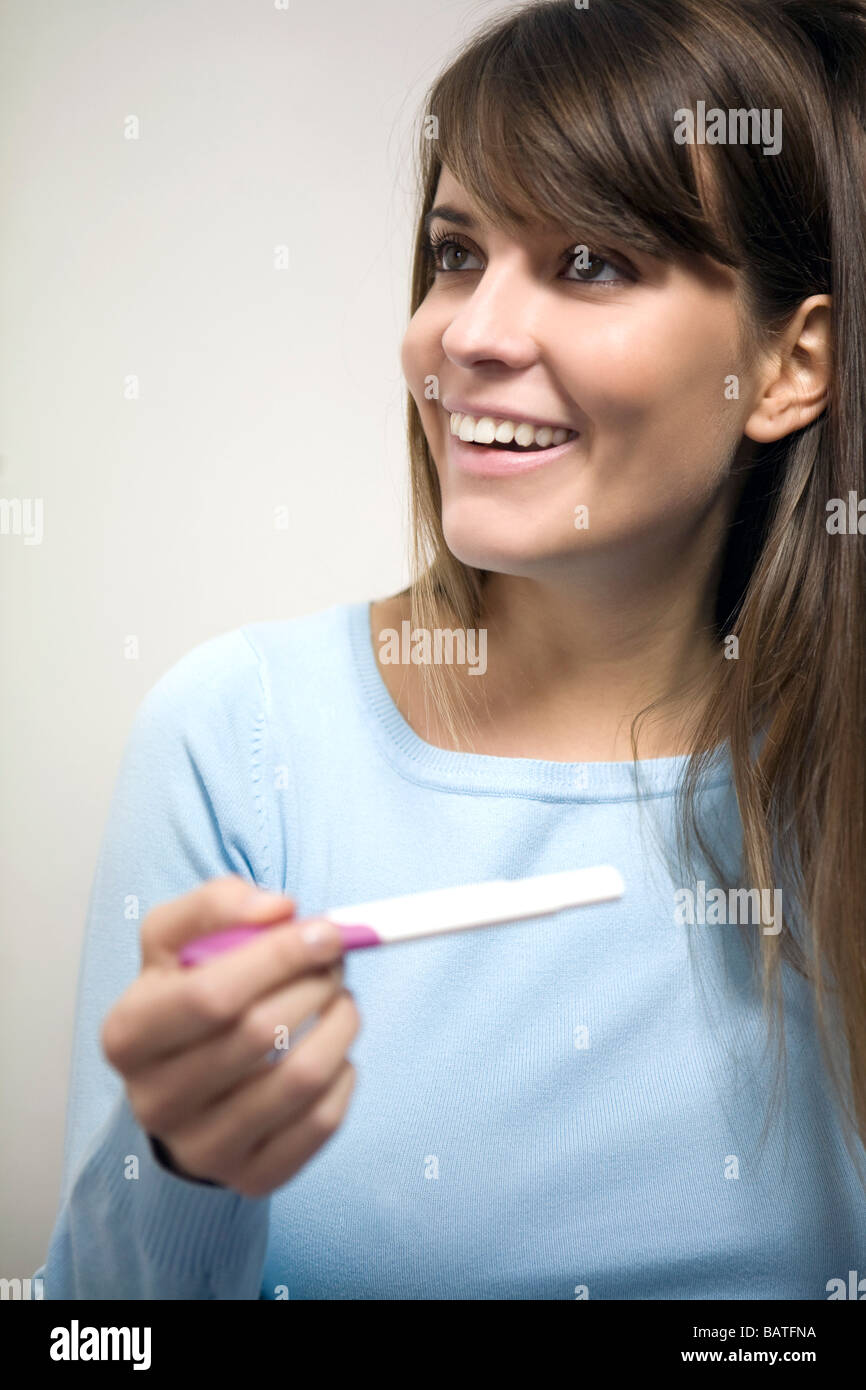 smiling young woman holding her pregnancy test Stock Photo - Alamy
