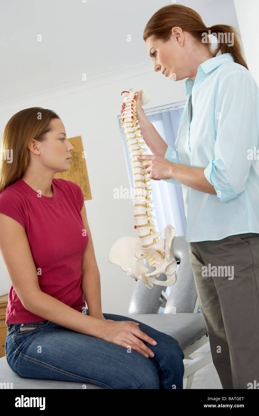 Chiropractor and patient.The chiropractor is using a model of the spine ...
