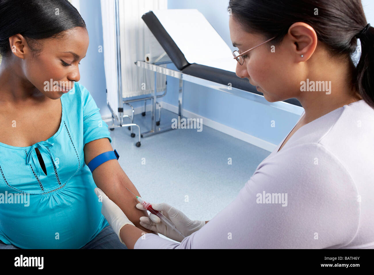 Obstetric examination. Midwife taking a blood sample from the arm of a ...