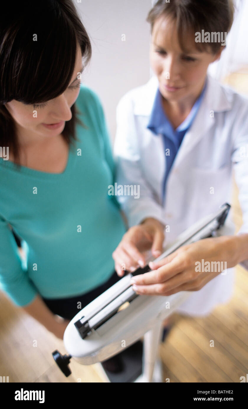 Weight check-up. General practice doctor adjusting the balance on ...