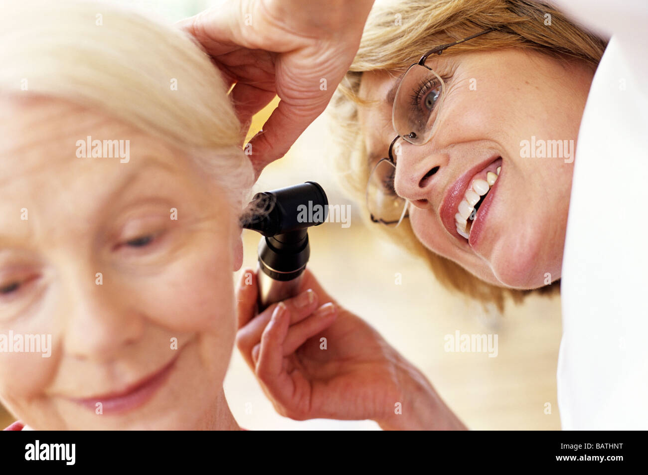 Ear examination. General practice doctor examining a 63-year-old woman ...