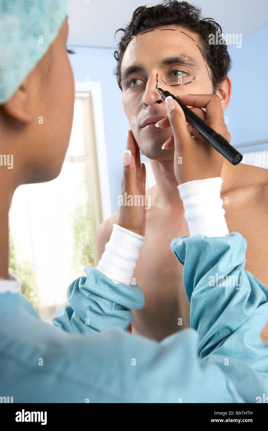 Cosmetic surgery. Surgeon drawing marks on a patient face in ...