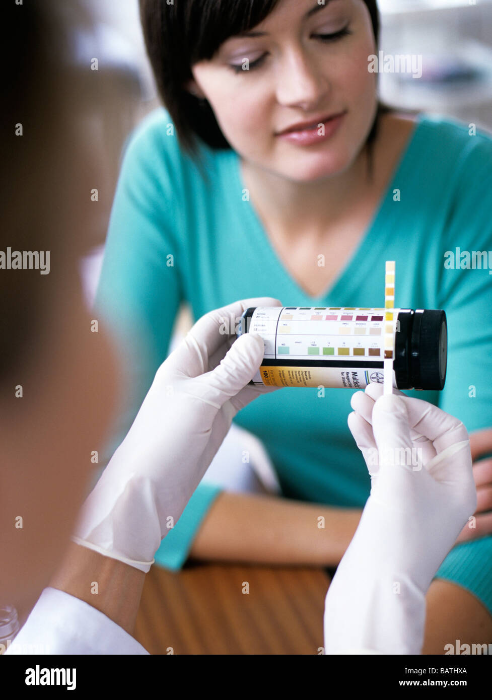 Urine analysis. Generalpractice doctor comparing a multiple test stick ...
