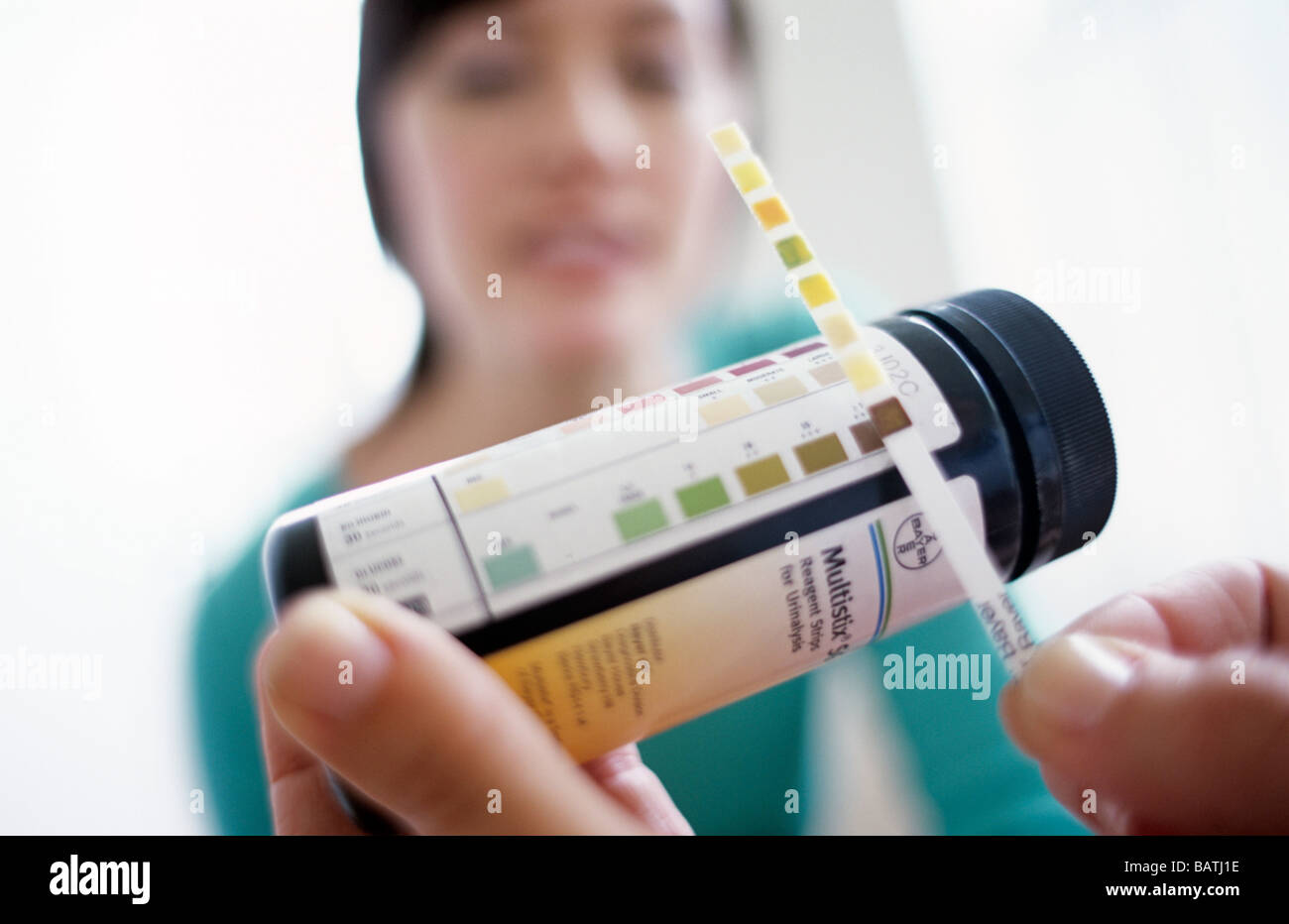 Urine analysis. General practice doctor comparing a multiple test stick ...