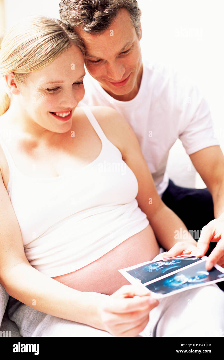 Expectant parents looking at an ultrasound scan of their unborn child ...
