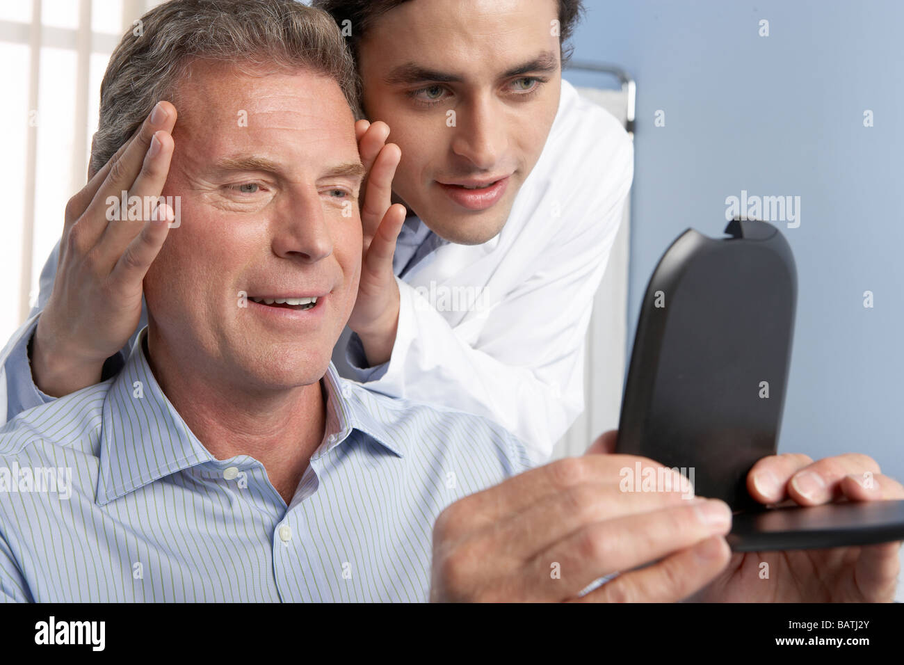 Cosmetic surgery. Doctor pulling back the brows of a middle-aged man ...