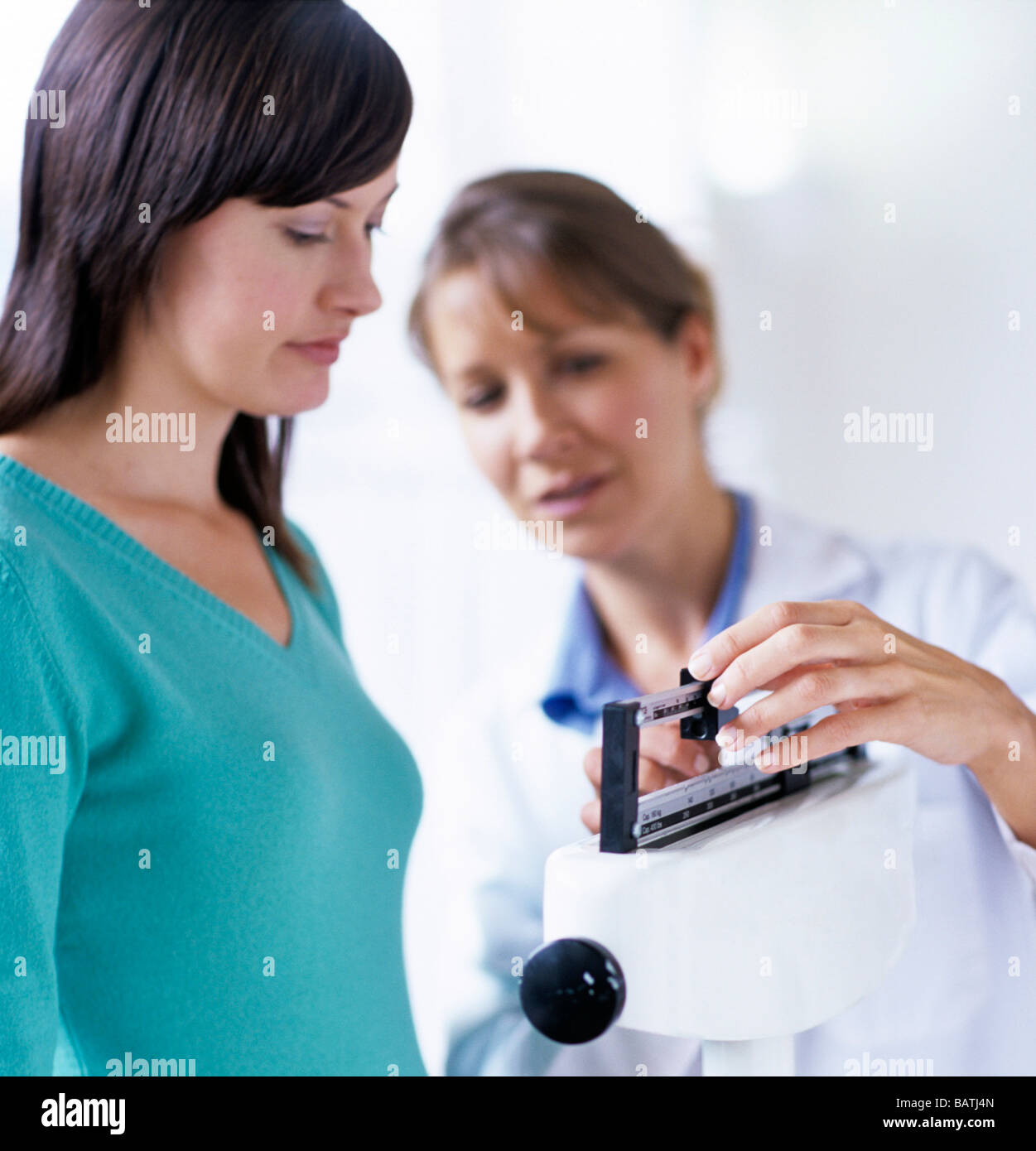 Weight check-up. General practice doctor adjusting the balance on ...