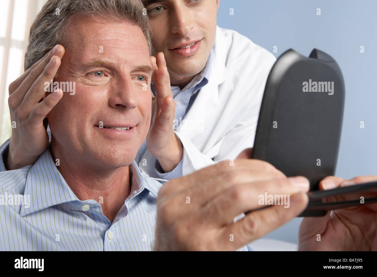Cosmetic surgery. Doctor pulling back the brows of a middle-aged man ...