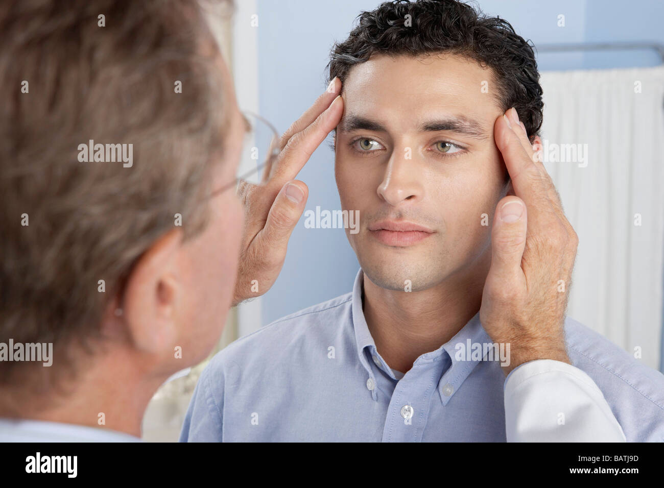 Cosmetic surgery. Doctor pulling back the brows of a middle-aged man ...