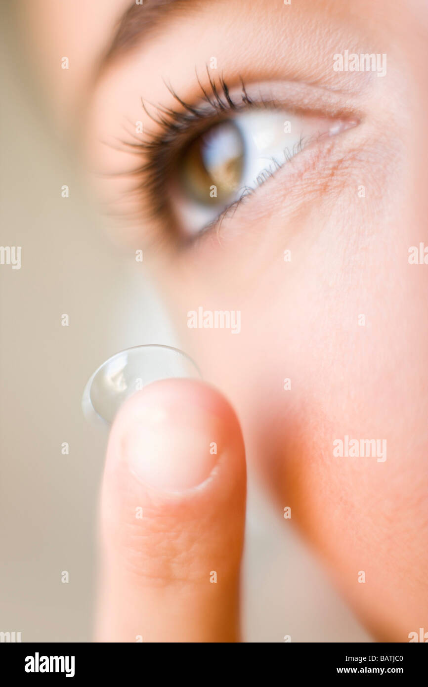 Contact lens use. Woman inserting a disposable (soft) contact lens ...